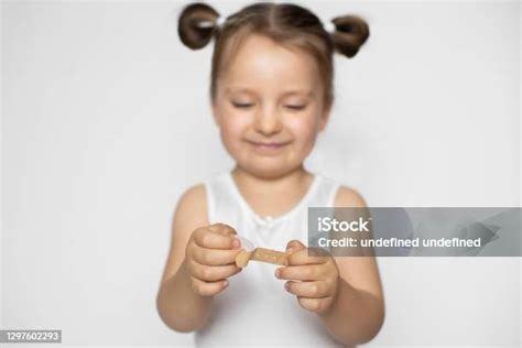 행복한 작은 만족 아이 소녀 흰색 탱크 탑을 입고 두 포니 테일 의료 접착제 석고 붕대를 열고 미소와 그녀의 손을보고 클로즈업 샷 손에 집중 아이에 대한 스톡 사진 및 기타