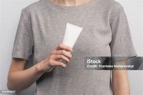 흰색 배경에 격리된 빈 흰색 화장품 튜브 크림을 바른 여성의 손이 화장품 튜브에 닿습니다 크림 핸드 로션의 개념 겨울 피부 관리 튜브에서 핸드 크림을 사용하는 여자 전체