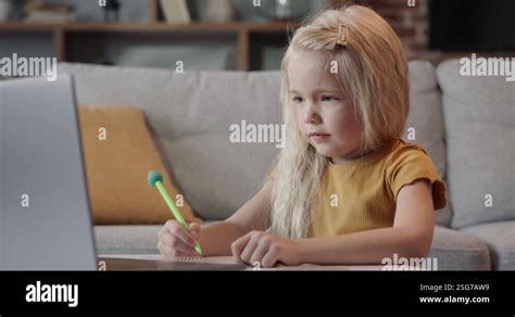 Primary School Girl Uses A Laptop And Learning Online Making Notes On Notepad Stock Video