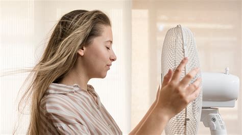 여름 더위 집에서 선풍기로 더위를 식히고 더운 날씨에는 고온으로 몸이 불편하고 극심한 폭염 중에는 선풍기에서 신선한 공기를 마시고 있다 에어컨에 대한 스톡 사진 및 기타