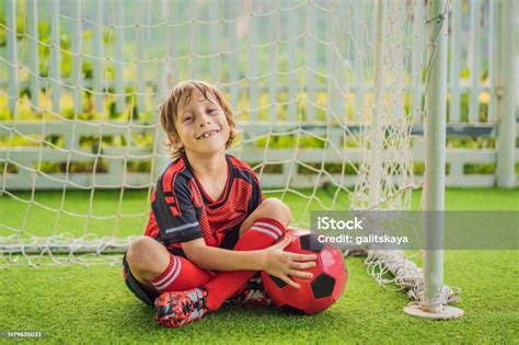 빨간 축구 유니폼을 입은 귀여운 소년이 야외에서 축구 축구를 하고 있다 아이들이나 아빠와 함께 스포츠를 하는 활동적인 아이 여름에 즐거운 미소를 짓는 행복한 소년 6 7