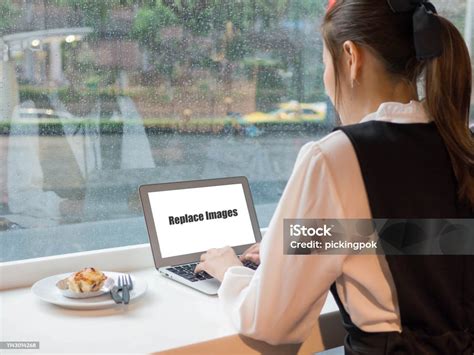 비와 외부 창 근처에 앉아있는 스마트 폰과 노트북을 사용 하 여 화이트 셔츠에 아시아 젊은 비즈니스 우먼의 측면도 및 노트북과