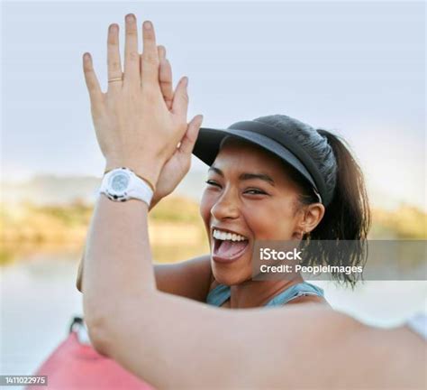 두 친구는 하이 파이브를 공유하고 야외에서 활동하면서 성공을 축하합니다 쾌활한 여성이 카약을 타고 파트너에게 동기를 부여하면서 여름에 호수에서 수상 활동을 즐기면서 축하에