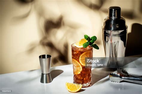 보드카 럼 데킬라 진 주류 레몬 주스 콜라 및 얼음을 곁들인 롱 아일랜드 아이스 티 칵테일에 레몬 슬라이스와 민트로 장식 된 하이볼 유리 베이지색 배경 하드 라이트 아이스