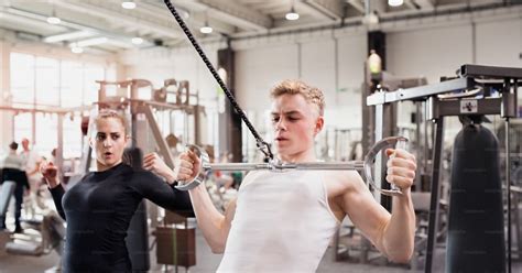 체육관에서 풀다운 머신에서 운동하는 개인 트레이너와 함께 잘 생긴 젊은 남자 케이블 웨이트 머신으로 운동하는 보디빌더 사진 Unsplash의 슬로바키아 이미지