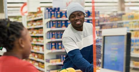캐주얼복을 입은 행복한 청년이 계산대 라인에 식품을 놓고 흑인 여성 계산원이 스캔하는 동안 사진 Unsplash의 고객