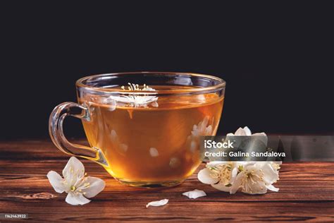 어딘가에 자스민 또는 모의 오렌지라고 하는 필라델푸스의 꽃과 어두운 나무 테이블에 향기로운 재스민 차컵 재스민 차에 대한 스톡