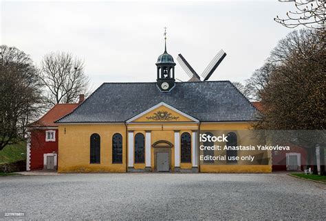 아치형 창문이 있는 고전적인 노란색 건물의 그림 같은 전망 종탑 나무로 둘러싸여 있고 상징적인 풍차가 고요한 분위기를 자아내는 모습 0명에 대한 스톡 사진 및 기타 이미지