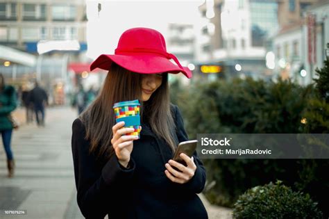 빨간 모자를 입고 거리에 스마트 폰 커피와 문자 메시지를 마시는 젊은 여자 가까운에 대한 스톡 사진 및 기타 이미지 가까운 가을 거리 Istock
