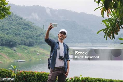 쾌활 한 젊은 아시아 여행자 남자 사진 또는 모바일 스마트폰 야외에서 아름 다운 배경으로 Selfie 라이프 스타일과 휴식