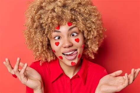 Premium Photo Funny Curly Haired Blonde Young Woman With Sticky Hearts On Face Prepares For St