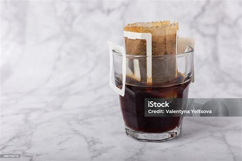 커피 백 커피 원두 흰색 컵을 텍스처 테이블에 떨어 뜨립니다 컵에 양조하기 위한 분쇄 커피 종이 봉지 드립 커피 필터 포장 복사할 장소 텍스트를 위한 위치입니다 0명에 대한