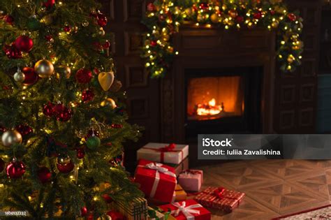 벽난로가 있는 고전적인 크리스마스 장식 인테리어 거실 도서관 붉은 황금 장식 장식이 있는 크리스마스 트리입니다 현대적인 고전적인 스타일의 인테리어 디자인 아파트 집에서