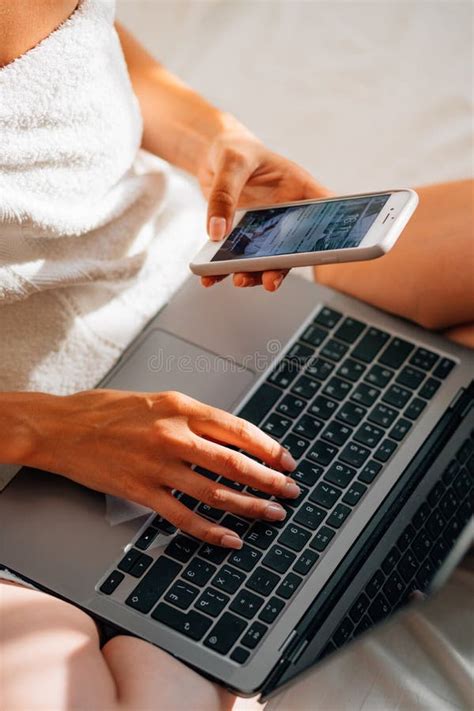 Close Up Of Young Woman Scrolling With Finger On Mobile Screen While Resting On Bed With Laptop