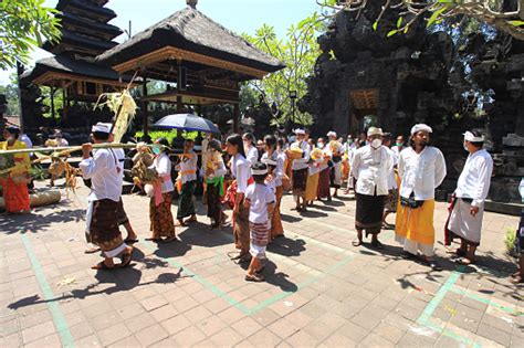 인도네시아 이스트 발리의 고아 라와 사원 내부 장면에서 케바야와 바틱 사롱과 같은 전통 의상을 입은 사람들과 우뎅 모자를 쓴 남자들 어떤 사람들은 머리에 제물을 들고