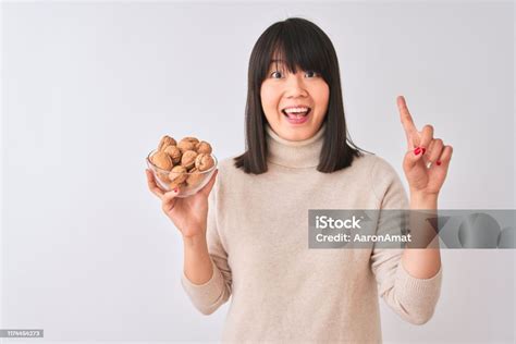 젊은 아름다운 중국 여자는 행복한 얼굴 번호 하나 손가락을 가리키는 아이디어 또는 질문으로 놀란 고립 된 흰색 배경을 통해