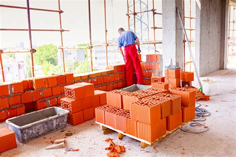 붉은 벽돌 더미가 있는 팔레트 작업자는 빨간 블록과 모르타르로 벽을 짓고 있습니다 Crash Site에 대한 스톡 사진 및 기타 이미지 Crash Site 건설 현장