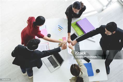 테이블 위에 손을 모으고 있는 사업가들의 윗모습 책상 위에 놓인 아래 그래프 젊은 사업가와 사업가는 단합과 팀워크 지원을 보여주는 손을 쌓습니다 개념에 대한 스톡 사진 및