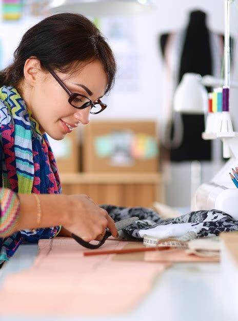 Diseñador De Moda Que Corta La Materia Textil Al Lado De Una Máquina De Coser Foto Premium
