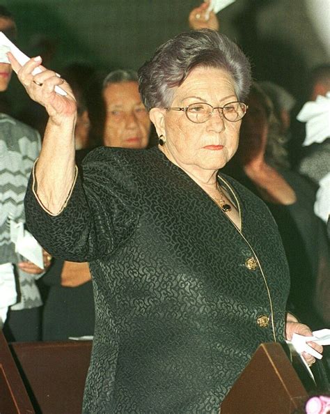 An Older Woman Holding A Remote Control In Her Right Hand And People
