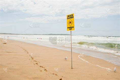 海滩关闭的标志。尽管有警告，人们仍在游泳和冲浪