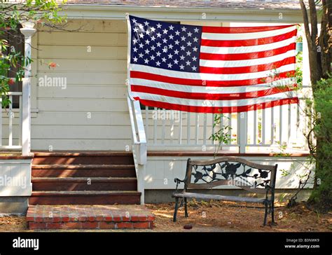American Flag Hanging On The Front Porch Of An Old Farmhouse Stock