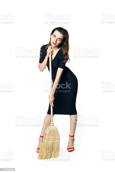 검은 드레스와 빨간 신발에 아름다운 갈색 머리 여자 는 흰색 배경에 고립 된 주부처럼 빗자루와 함께 포즈를 취하고 30 34세에