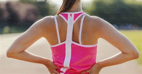 스포츠 옷장에 여자의 뒷면입니다 분홍색 피트니스 티셔츠를 입은 잘생긴 소녀가 엉덩이에 손을 얹고 있는 사진 뒤로 초점 및 흐릿한 배경 사진 Unsplash의 성인 이미지