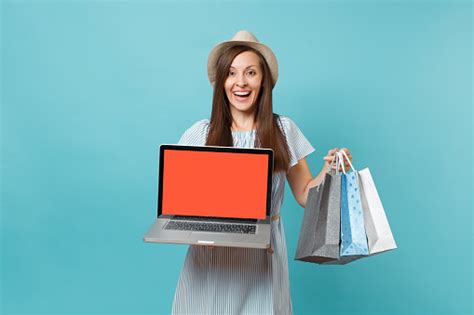 여름에 여자의 초상화 드레스 들고 쇼핑 후 구매와 패키지 가방 노트북 Pc 컴퓨터 빈 화면 블루 파스텔 배경에 고립 밀 짚 모자 광고에 대 한 공간을 복사 합니다 가방에