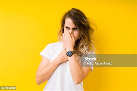 노란색 배경 뭔가 냄새 나 고 역 겨 운 냄새 참을 냄새 코에 손가락으로 잡고 숨을 젊은 아름 다운 금발 여자 나쁜 냄새 개념입니다 곱슬 머리에 대한 스톡 사진 및 기타