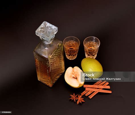 계피와 아니스를 곁들인 배 리큐어 잘 익은 과일과 향신료 옆에있는 검은 배경의 크리스탈 그릇에 담긴 수제 알코올 0명에 대한