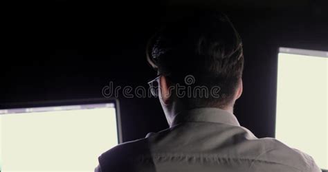 Programmer Man Is Working In The Office Overtime Late At Night Sitting Before Two Monitors And