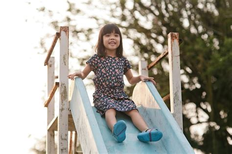 Premium Photo Portrait Of Girl Sliding Down On Slide In Park