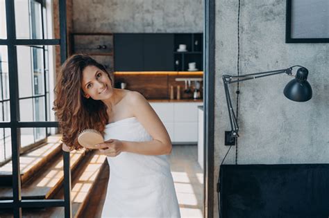 목욕 후 머리카락을하는 수건에 싸인 행복한 소녀 여자는 곱슬 머리를 브러시로 빗어 낸다 가정 생활에 대한 스톡 사진 및 기타