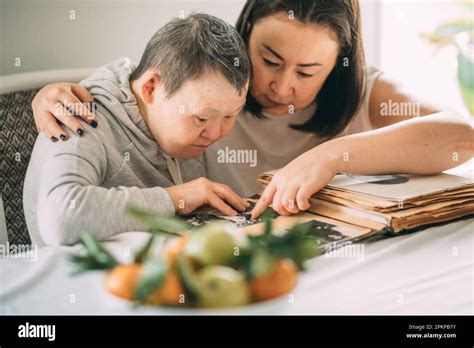 smiling elderly woman with down syndrome looks at photos in an old