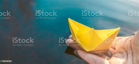 손에 노란색 외로운 떠 다니는 종이 보트 큰 푸른 봄 웅덩이 강물에 화려한 범선 따뜻하고 습한 비오는 날씨 안녕하세요 봄 가을 아이들은 놀고 야외에서 거리를 즐깁니다 미래