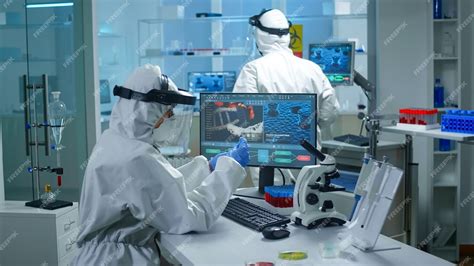 실험실 기술자가 그녀의 혈액 샘플을 가져 오는 동안 Pc에서 일하는 Ppe 소송에서 화학자 의사 무료 사진