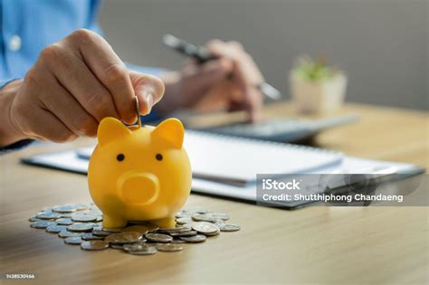 사업가는 책상과 돼지 저금통 동전 더미에서 저축을 계산합니다 투자 및 저축 가족 지출 계획 은퇴시 이자율과 배당금을 계산합니다 경제에 대한 스톡 사진 및 기타 이미지