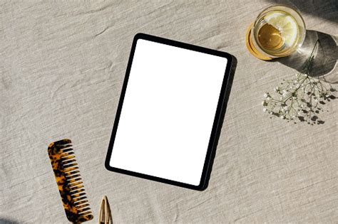 빈 화면 태블릿 모형 레몬 석고 꽃 린넨 식탁보와 테이블에 머리 빗물 물 한 잔 플랫 레이 상단 보기 북유럽 스칸디나비아 스타일