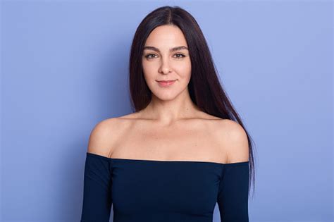 매력적인 미소와 카메라를보고 예쁜 여자의 초상화 맨손으로 어두운 파란색 드레스를 입고 행복한 소녀 긴 직선 머리와 슬림 사랑스러운 세련된 모델 아름다움과 관리 개념 갈색