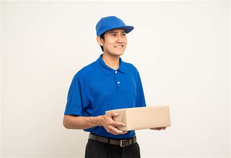 파란색 유니폼을 입은 아시아 남자는 격리된 흰색 배경에 상자 소포 판지를 들고 서 있습니다 웃는 남성 서비스 노동자 배달 택배 및 배송 서비스 고객에 대한 스톡 사진 및