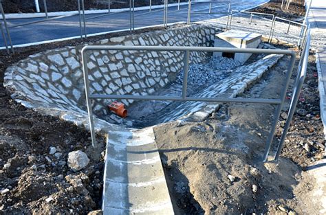 화강암 돌로 포장된 하수도 배수구와 제방은 고속도로에서 도랑으로 빗물을 배수하여 배수 그리드가있는 파이프를 통해 물이 하수구로 느려지는 유지 저수지로 흘러 들어갑니다 0명에