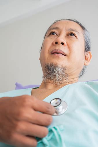 노인 환자 불행의 개미 눈 보기 고통 앞으로 찾고 아픈에서 슬픔과 심장에 청진기를 사용하여 의사 의사 또는 간호사는 병원에서 노인 환자 건강 입원을 치료 간호사에 대한 스톡