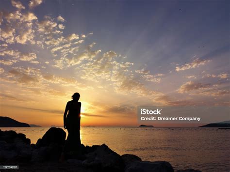 에게 해의 일몰 동안 해변에 서 있는 롱 스커트를 입은 젊은 여성의 실루엣 건강한 생활방식에 대한 스톡 사진 및 기타 이미지 건강한 생활방식 관광객 구름 Istock