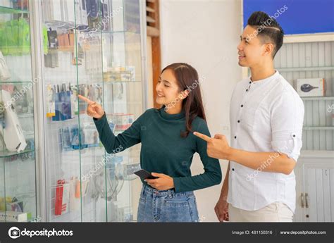 An Asian Woman And Man Standing Pointing To A Glass Display Case Stock Photo Odua 481150316