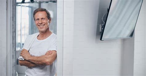 카메라를 향해 웃으며 손을 꼬고 있는 쾌활한 잘생긴 남자의 전면 모습 사진 Unsplash의 의류 이미지