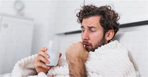 감기와 겨울 독감 바이러스를 앓고 있는 파자마를 입고 침대에 누워 있는 아픈 낭비된 남자 건강 관리 개념에 약 정제를 가지고 물 한 잔으로 약을 마신다 사진