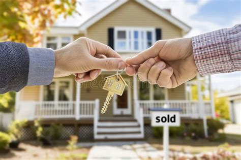 Homeownership Concept Hands Passing Keys To New Home With Sold Sign In
