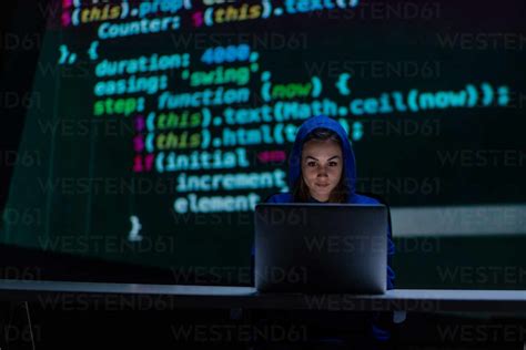 A Hooded Anonymous Hacker Woman By Computer In The Dark Room At Night Cyberwar Concept Stock Photo