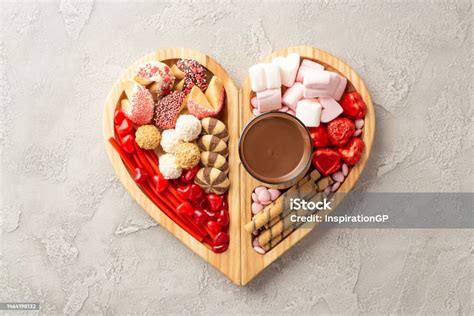 발렌타인 데이 개념입니다 과자 초콜릿 젤리 사탕 쿠키와 콘크리트 질감 배경에 핫 초콜릿의 유리 컵이 있는 나무 하트 모양의 서빙 트레이의 상위 뷰 사진 개체 그룹에 대한